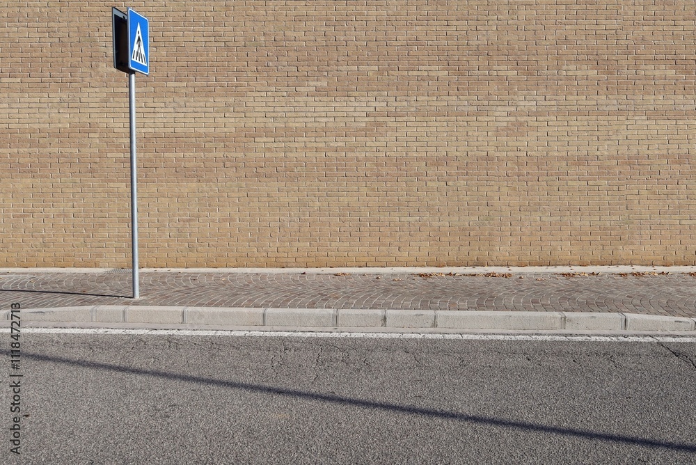 Yellow brick wall at the roadside with a pedestrian crossing sign on ...