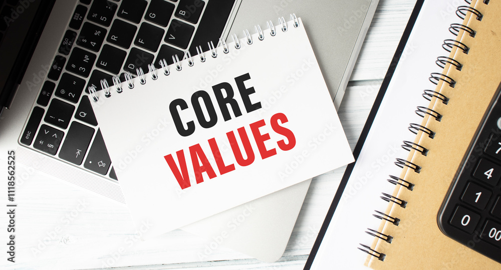 Notebook with text inside Core Values on table with coffee, laptop and ...