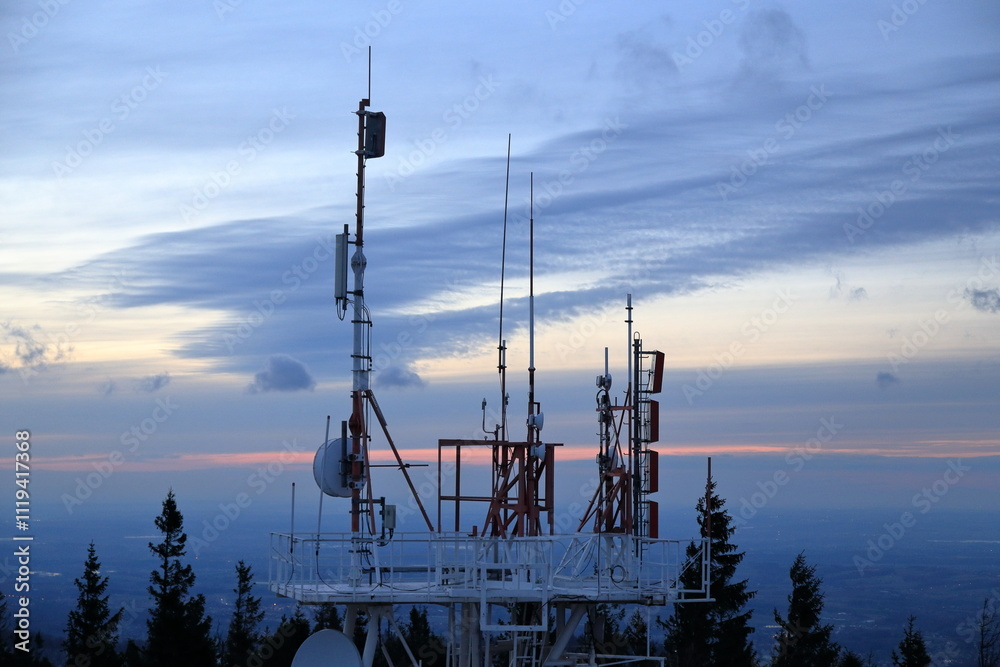 The photo depicts cell towers mounted on a massive mast, rising against ...