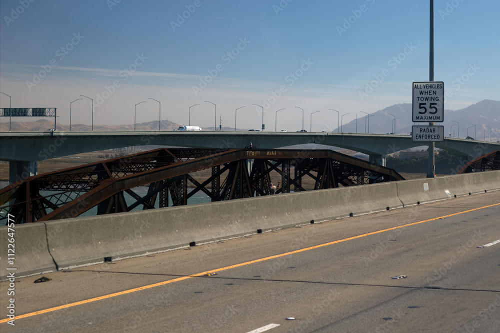 Bridge structure with warning sign along highway in sunny weather near ...