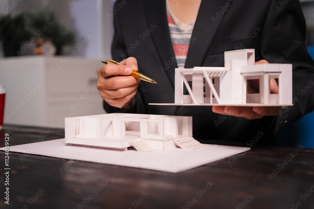 A salesman works late at night at his desk, surrounded by modern house ...