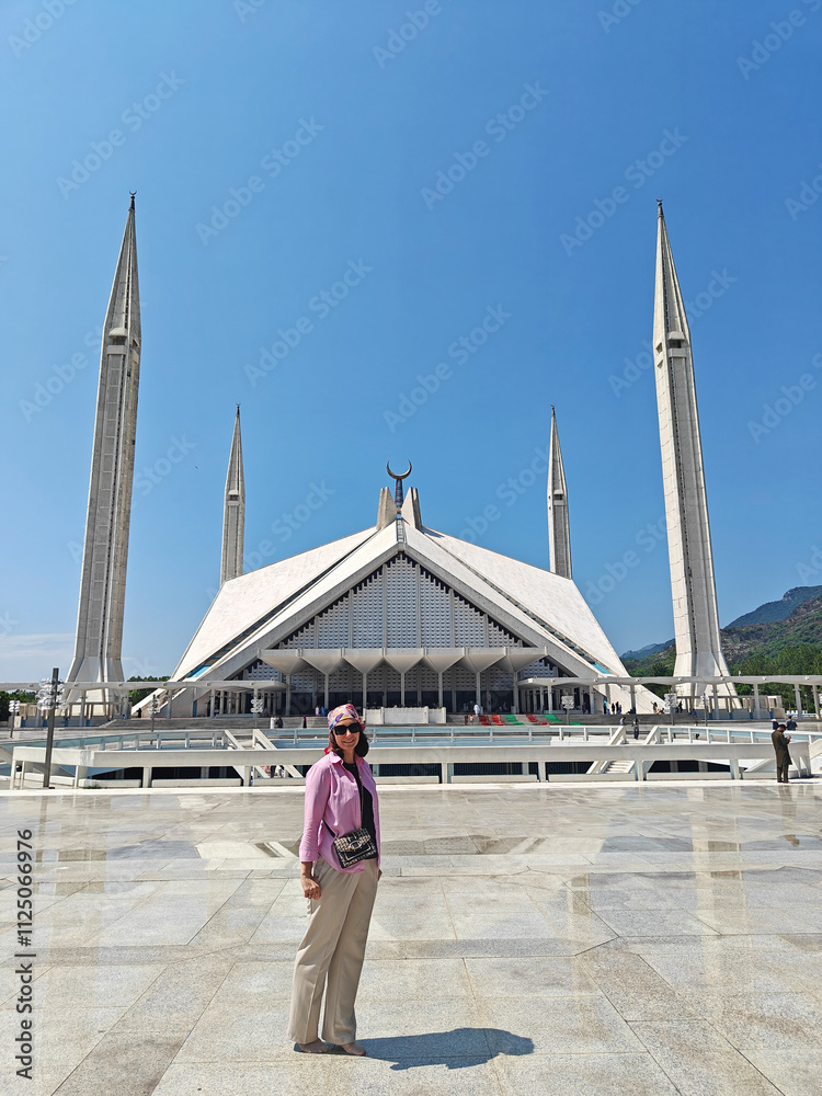A woman tourist stands against the backdrop of Shah Faisal Mosque in ...