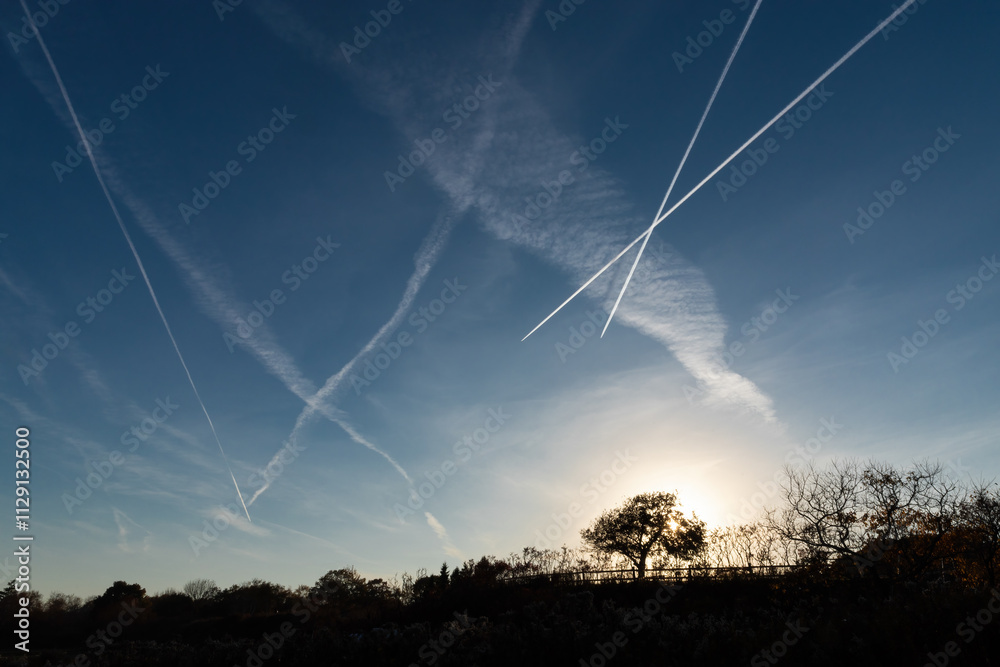 Sunrise or sunset with many numerous jet contrails showing air ...