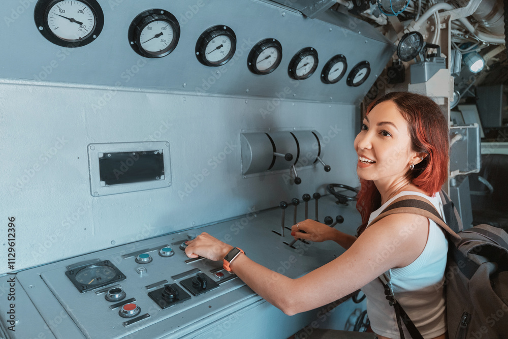 Young woman tourist exploring the interior of a submarine, operating ...