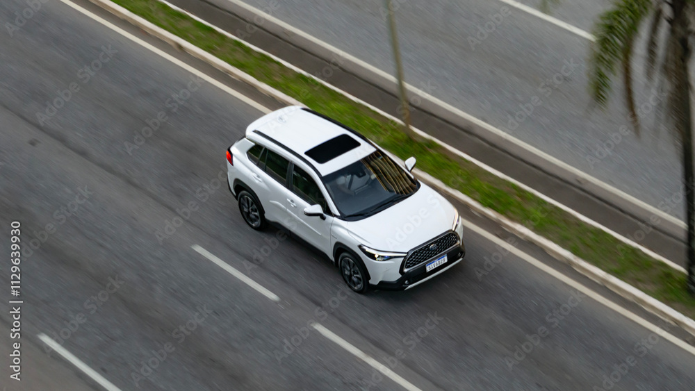 White Toyota Corolla Cross in movement, panning shot of hybrid suv on ...