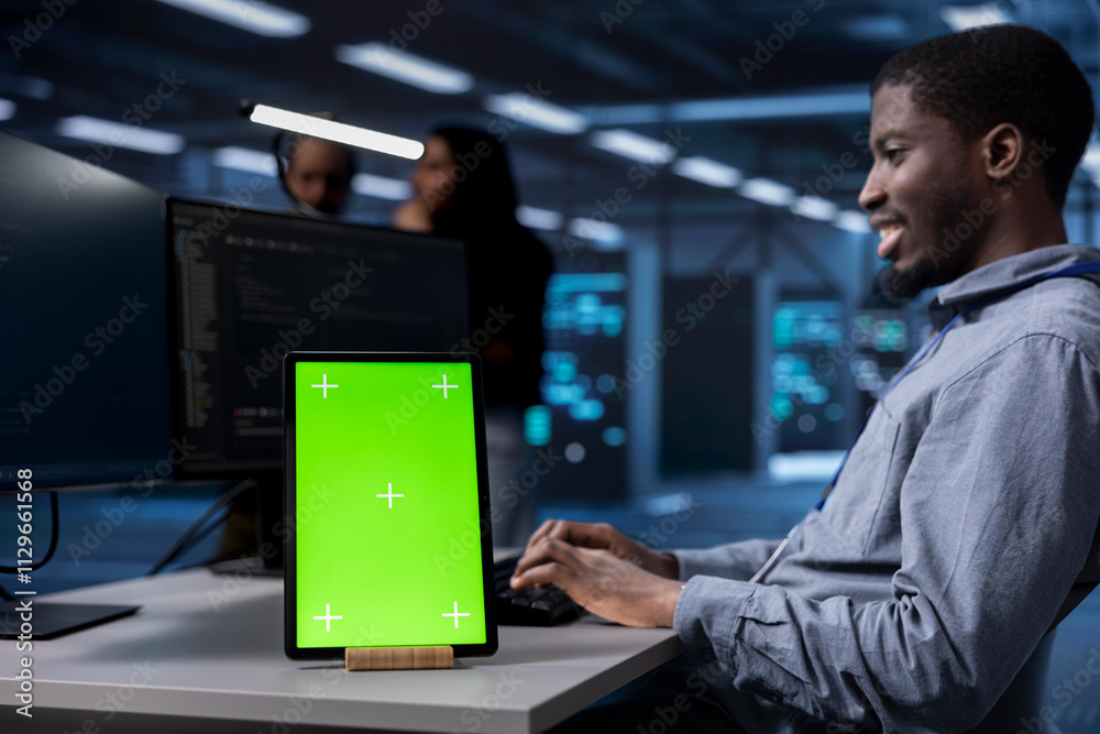 Smiling man working on green screen tablet in modern data center. Happy ...