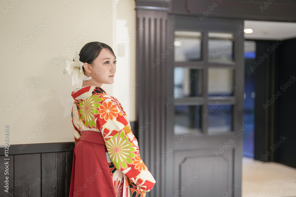 A Japanese woman in her 20s stands in front of an interior door wearing ...