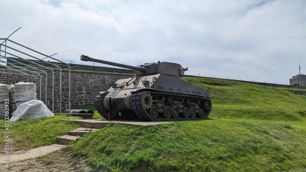 Sherman tank sitting on a grassy hill under a clear sky, a tribute to ...
