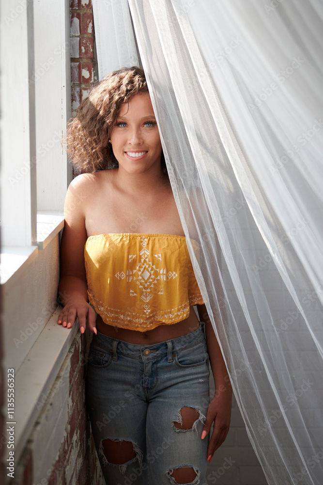 Beautiful young biracial woman poses for photo by window wearing a ...