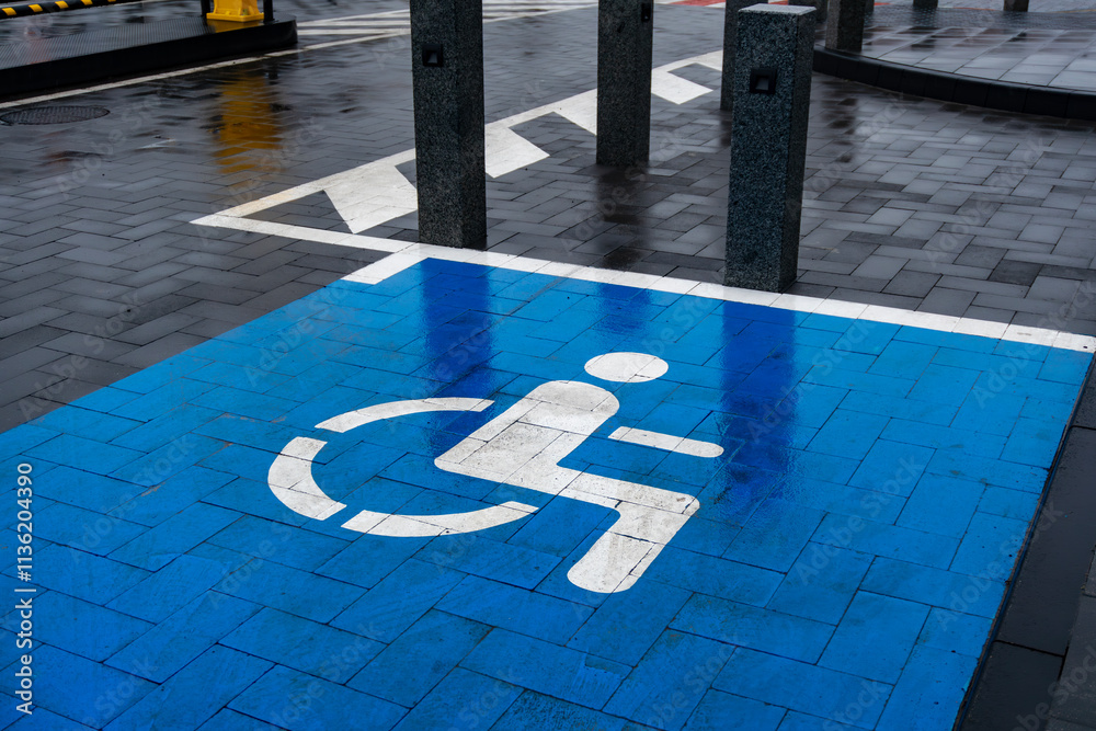 Bright blue accessible parking area is visible on a wet pavement ...