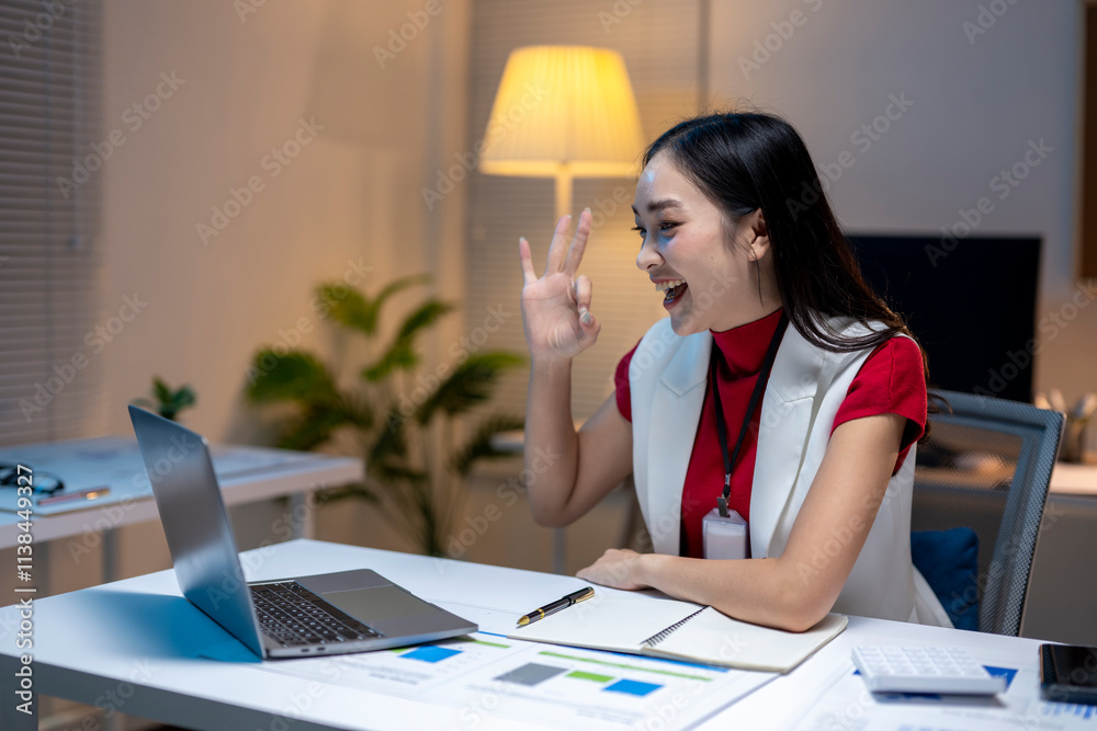Businesswoman is showing an ok sign with her hand while working late in ...