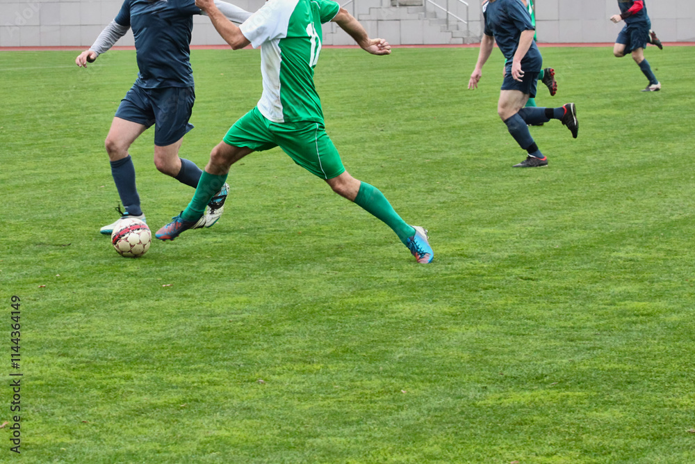 An attacker and a defender from football teams are fighting for the ...