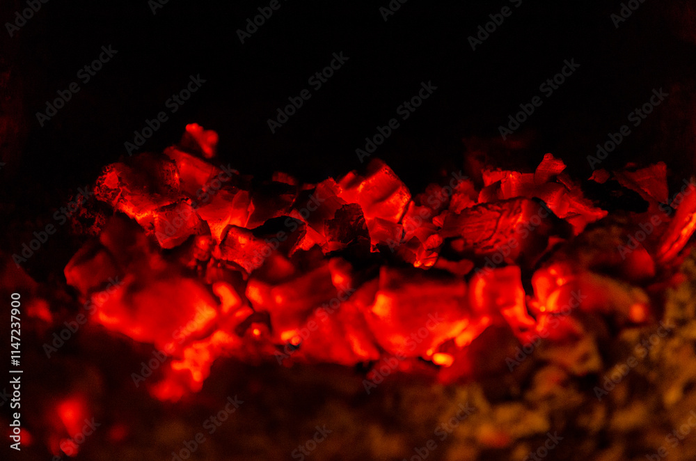 A close-up shot of glowing red hot coals in a fireplace. The fire has ...