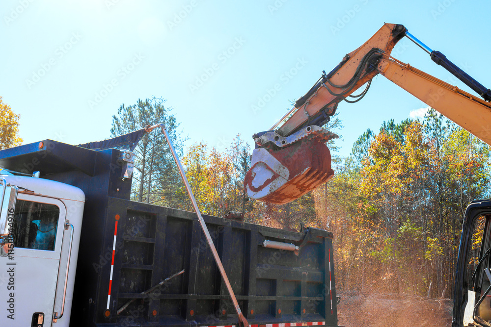 Large excavator lifts bucket of materials over dump truck at ...