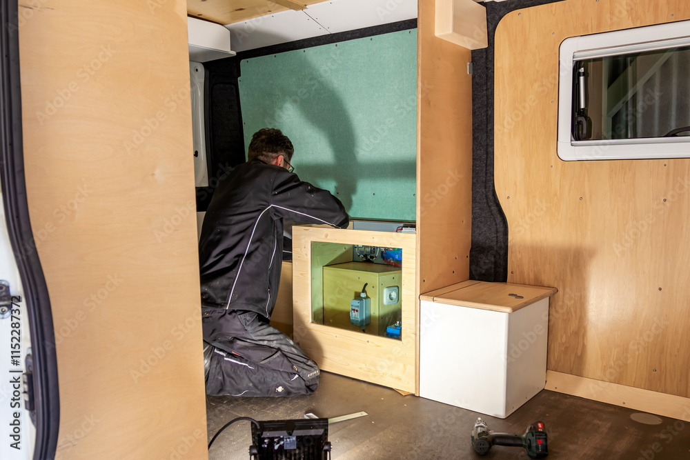 Camper van conversion. joiner working on enclosure door, protective ...