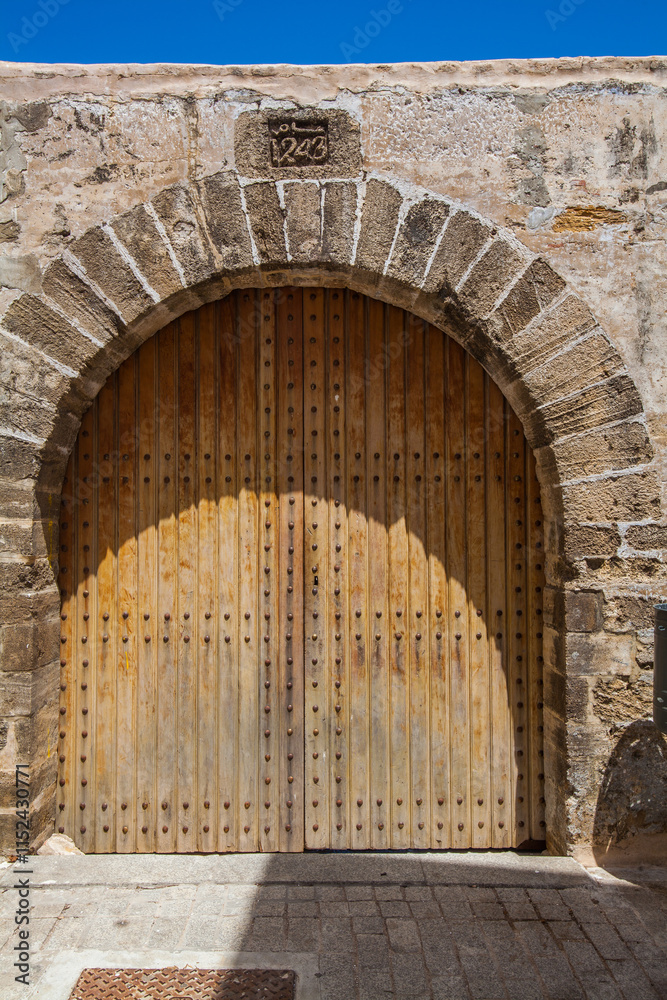 weathered wooden door with an arched stone frame and a keystone marked ...