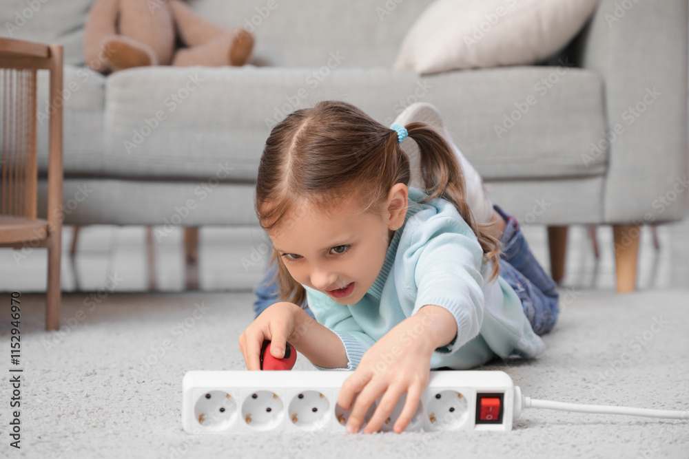 Cute little girl with screwing extension cord at home. Child in danger ...