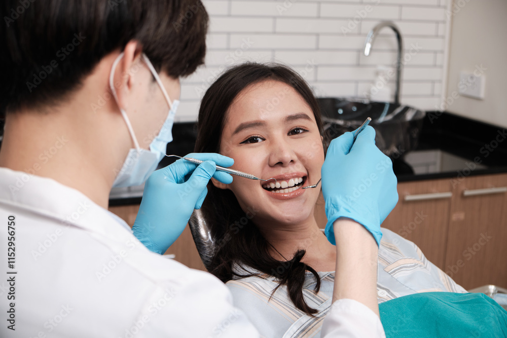 Asian male dentist examines beautiful young female patient's teeth ...