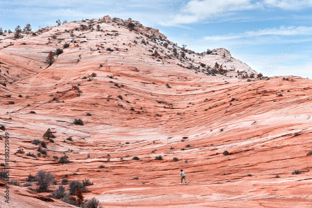 Man running to climb up a layered sandstone mountain rock to show scale ...