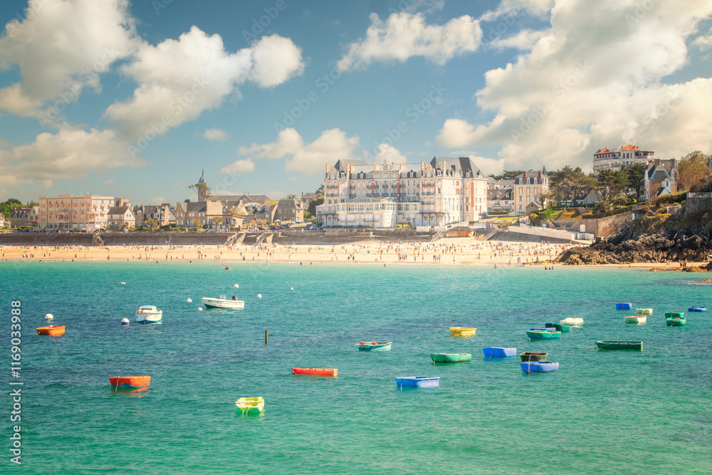 Plage en été sous un ciel ensoleillé avec bateaux, plage et batiments ...