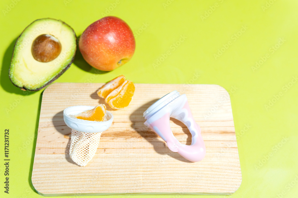 Baby fruit pacifier with orange avocado apple on green background with ...