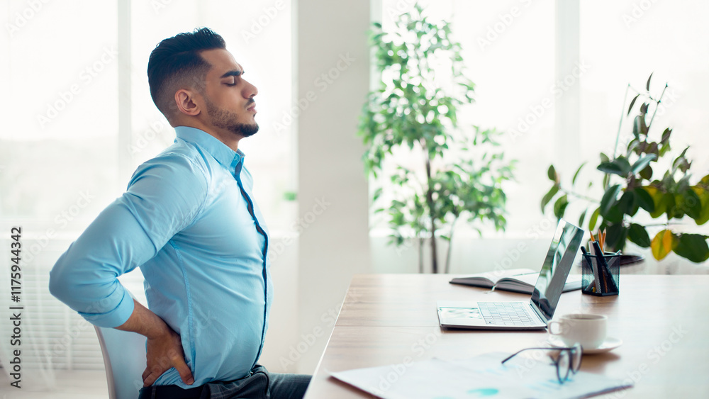 Young Arab businessman having acute back pain, massaging aching muscles ...