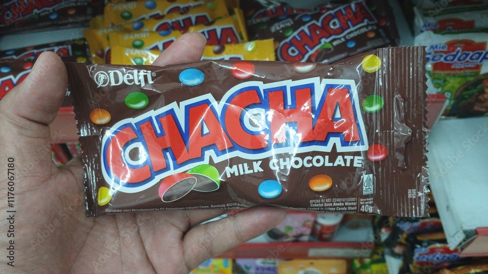 Hand holding Cha cha snack. Cha cha is peanut with milk chocolate which ...