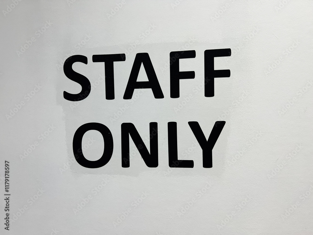 Sign indicating restricted area labeled as staff only on white textured ...