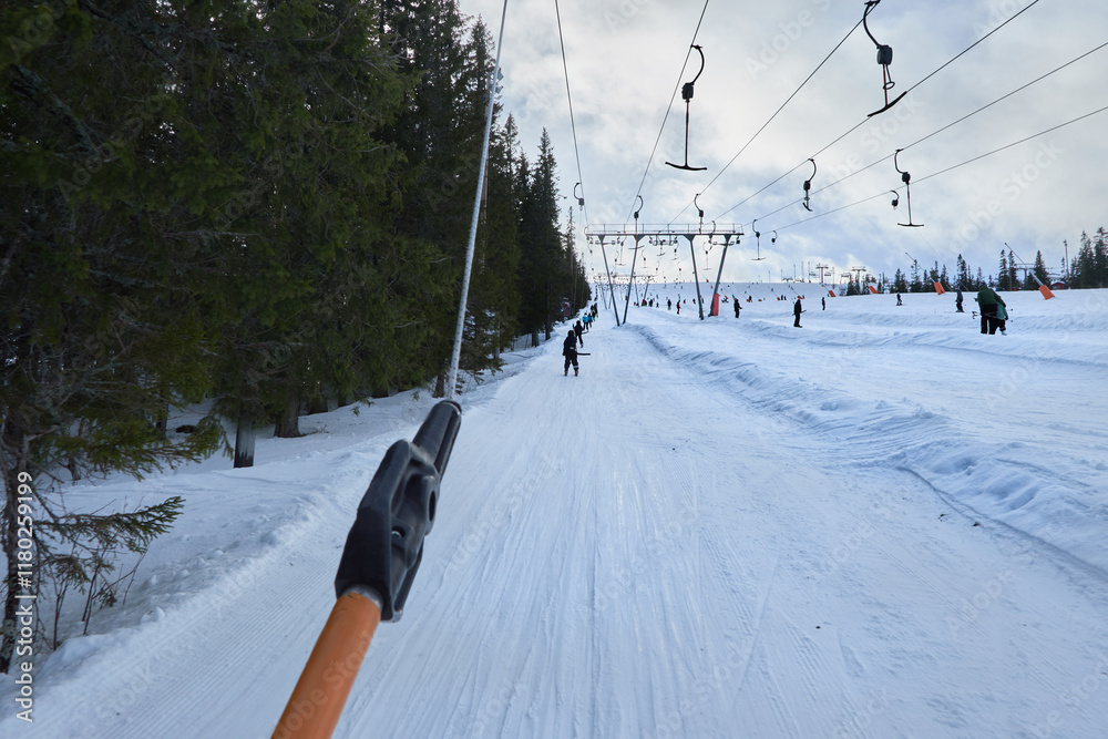 The view of riding a t-bar lift in going upwards a skiing slope in a ...