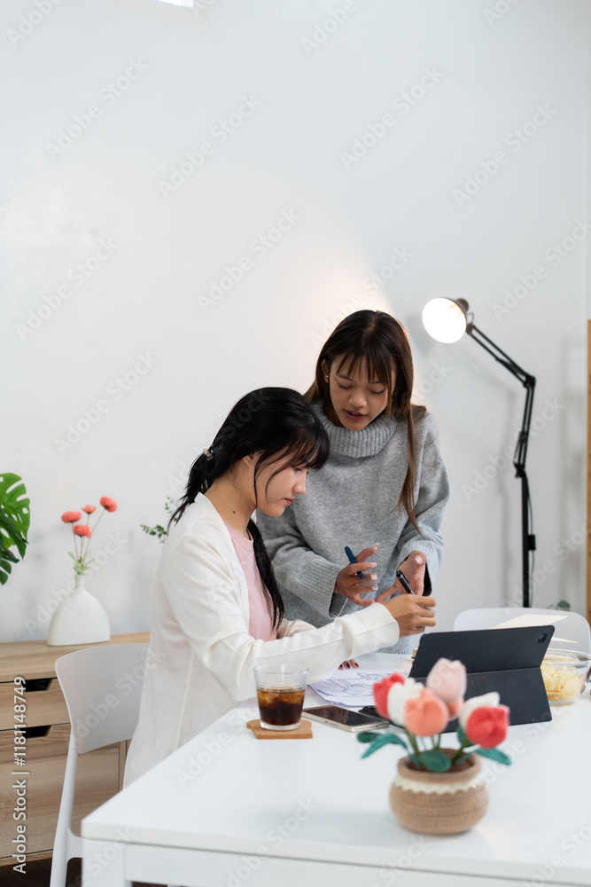 Female higher education student using laptop and studying book in home ...