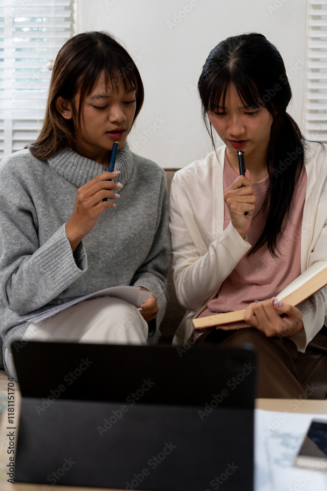 Female higher education student using laptop and studying book in home ...