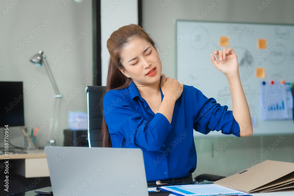 Asian businesswoman sits at her ergonomic desk, working on a laptop and ...