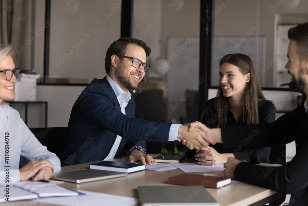 Smiling male colleagues, shareholders shake hands close deal at meeting ...