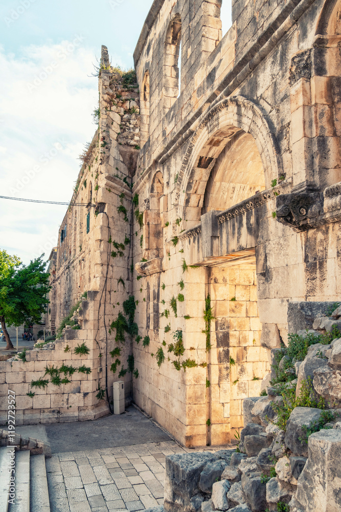 Sunlight illuminates the ancient stone walls and siilver gate and ...