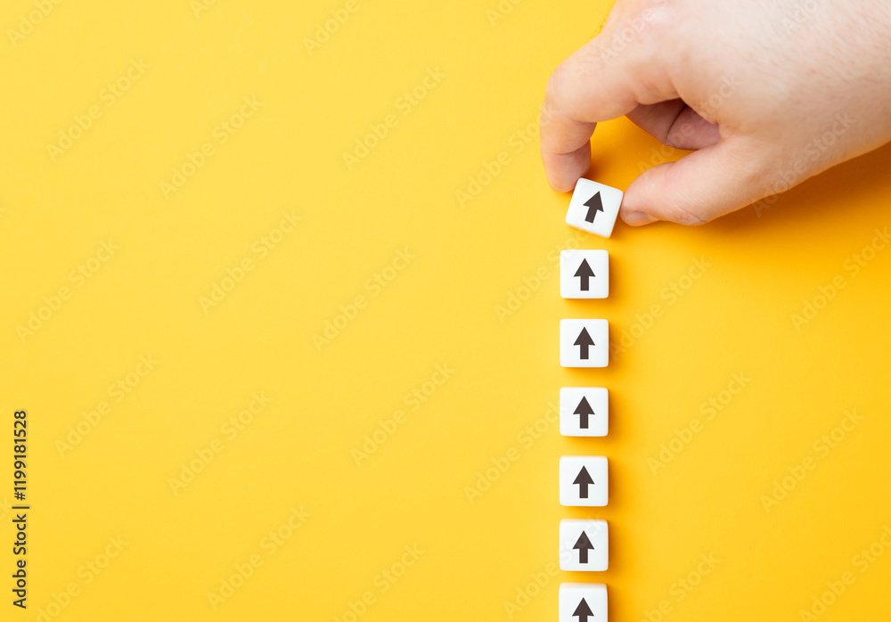 Hand making a row of arrows on a yellow background. Space for text ...