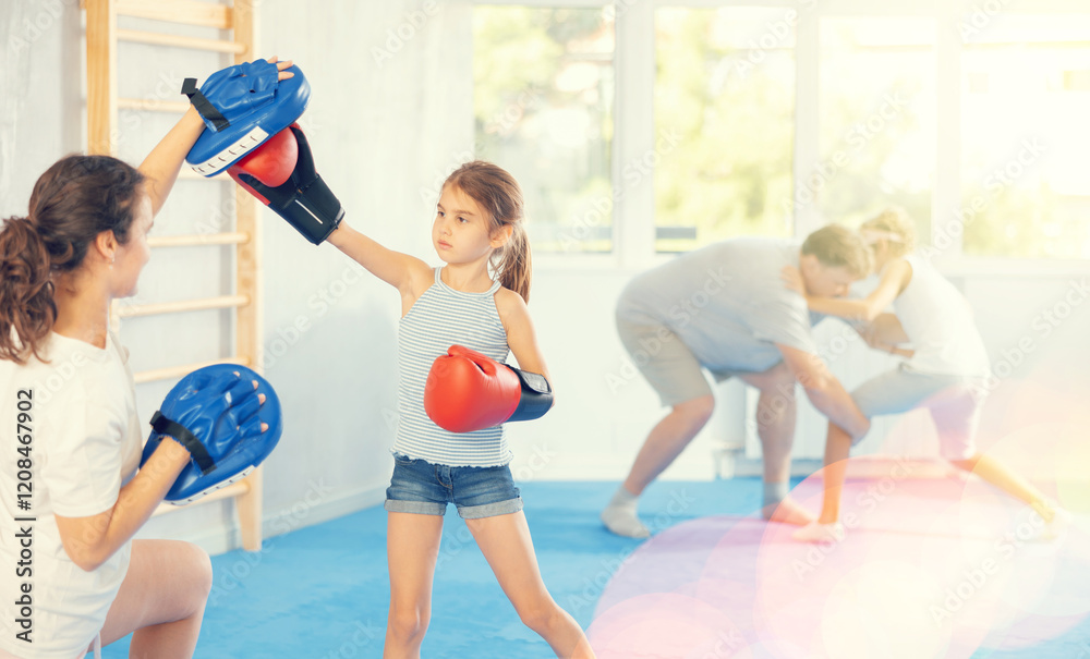 Girl and mother are boxing in gym, mom helps daughter child to work out ...