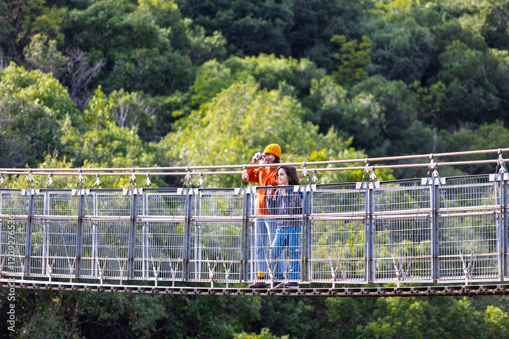 Family backpacking. Mother and son standing on suspension bridge ...