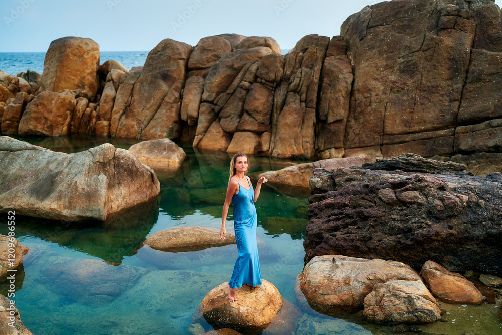 Elegant model in wet blue dress on rock in exotic tidal pool. Tropical ...