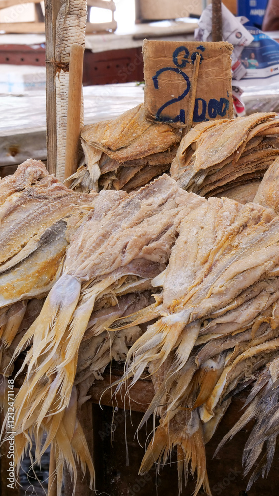 Vertical image of Pieces of whole and salted fish stacked in piles at a ...