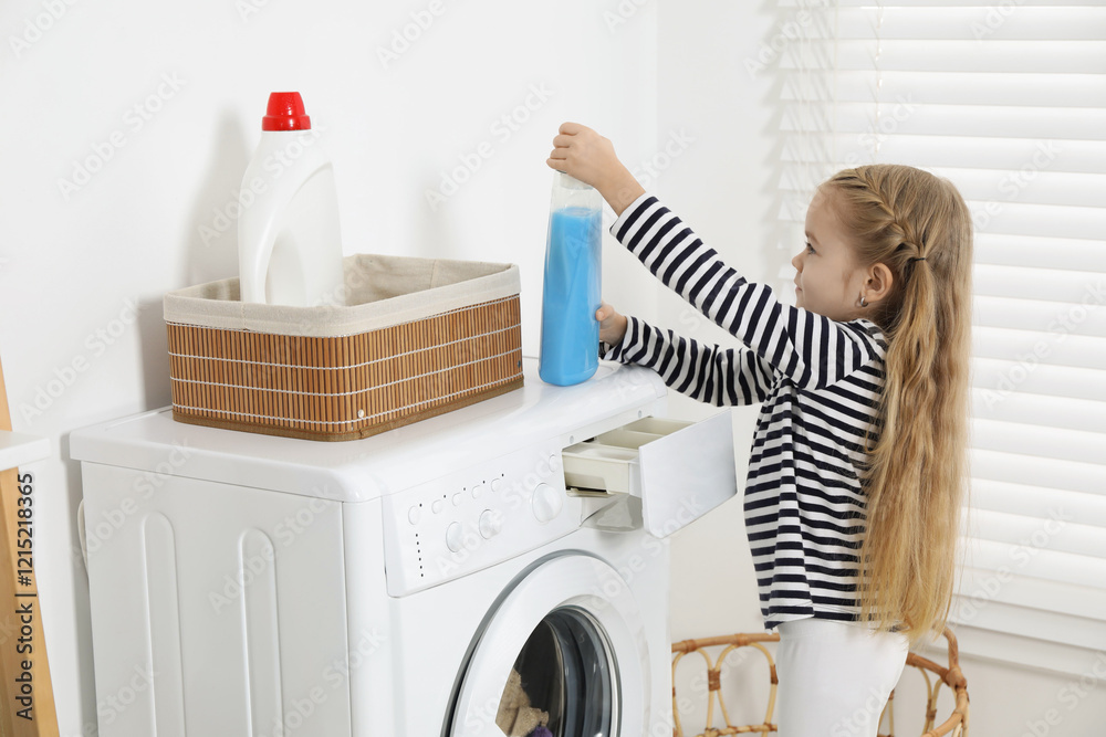 Little helper. Cute girl doing laundry at home Stock Photo | Adobe Stock