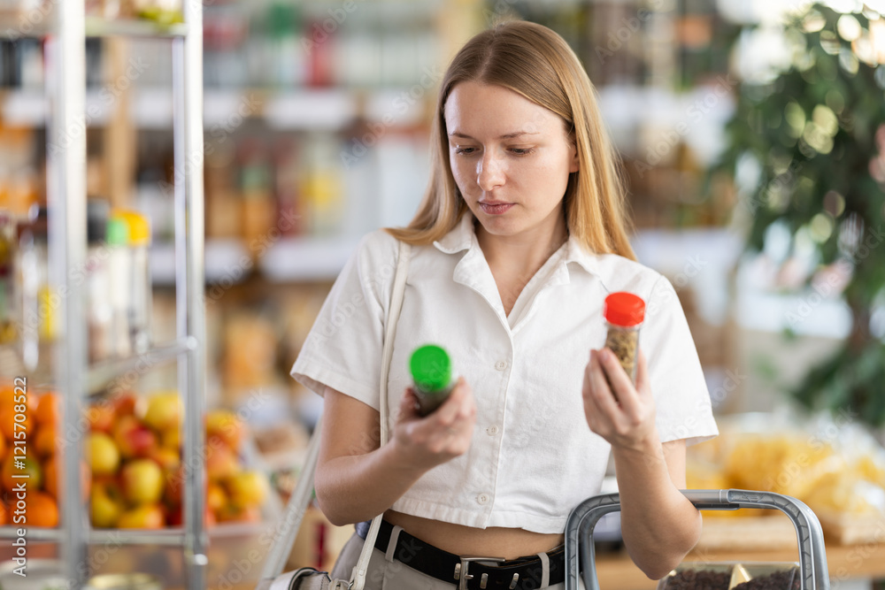 Female shopper selects aromatic ground spices in the produce section of ...
