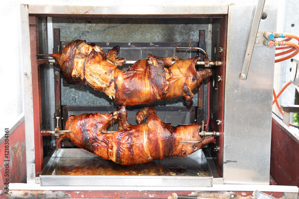 two pigs roasting piglets golden brown roast on a spit in rotisserie ...
