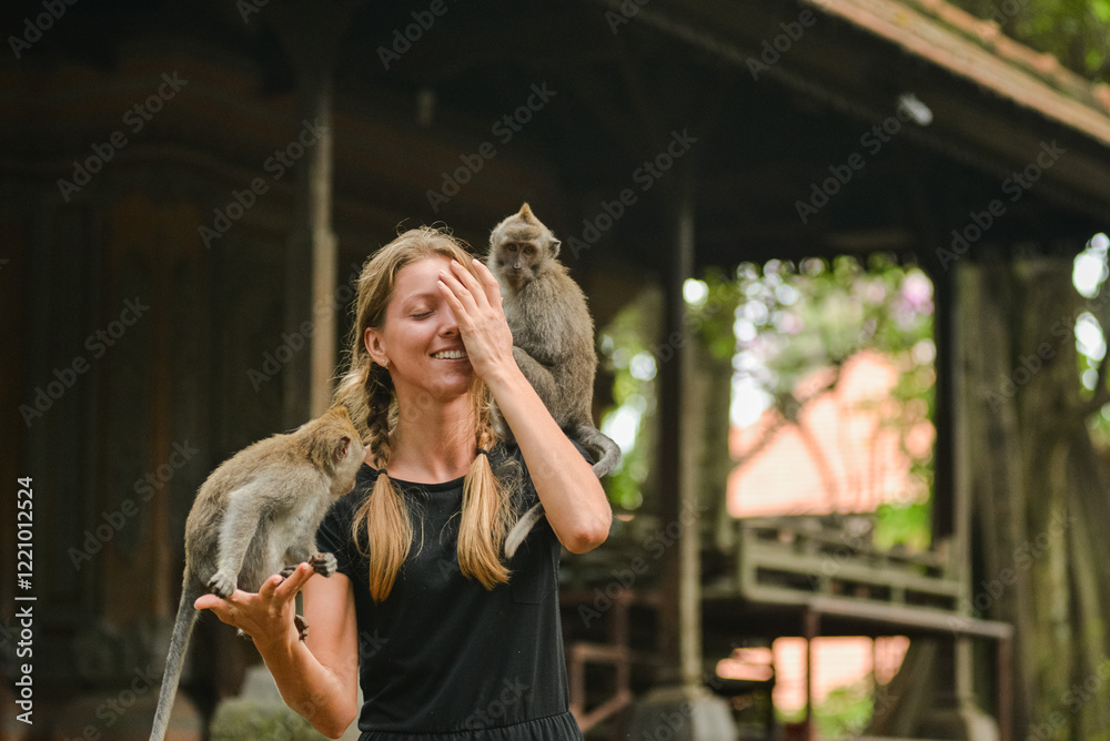 Smiling tourist woman interacting with monkeys at a sacred monkey ...