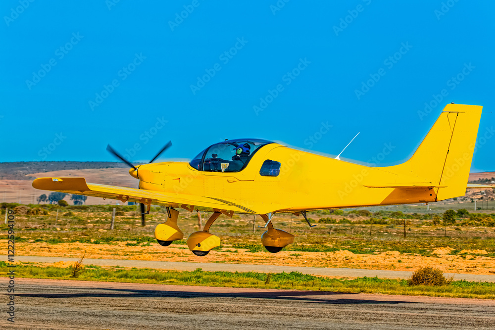 Bright yellow two-seater low-wing light-sport aircraft taking off from ...
