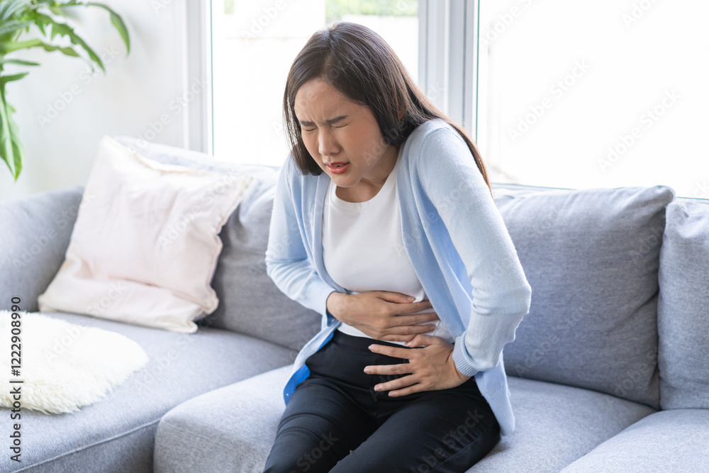 Foto de Stock Sick asian young woman in pain, hand holding belly, stomach pain from food ...