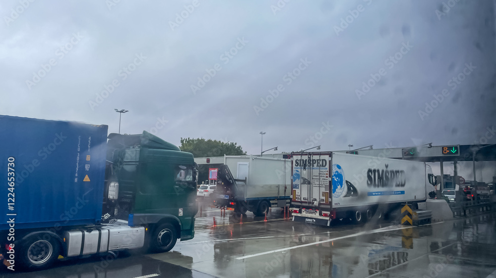 Trucks queue at a rainy border crossing, highlighting transportation ...