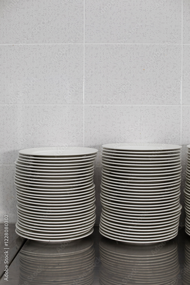 Many white clean plates stacked on the kitchen table. Clean dishes in a ...
