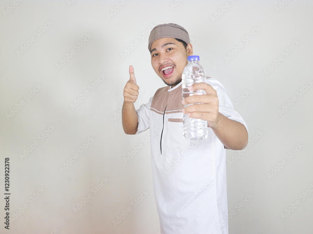 happy asian muslim man holding a bottle of mineral water and giving a ...