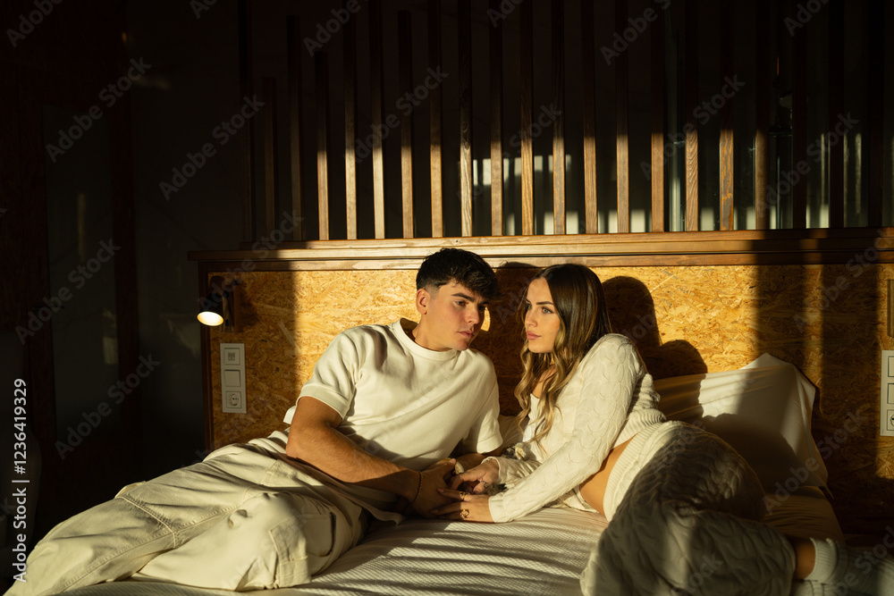 Young couple cuddling, wearing soft loungewear, holding hands and ...
