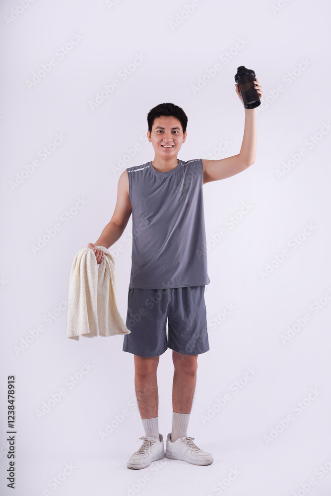 Full body image of an Asian guy wearing gym clothes, drinking water and ...